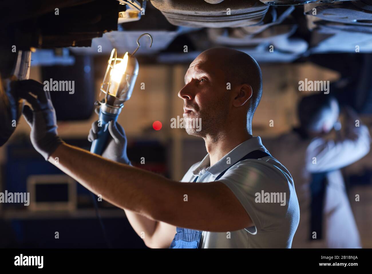 Waist up portrait of bald car mechanic inspecting vehicle while holding ...