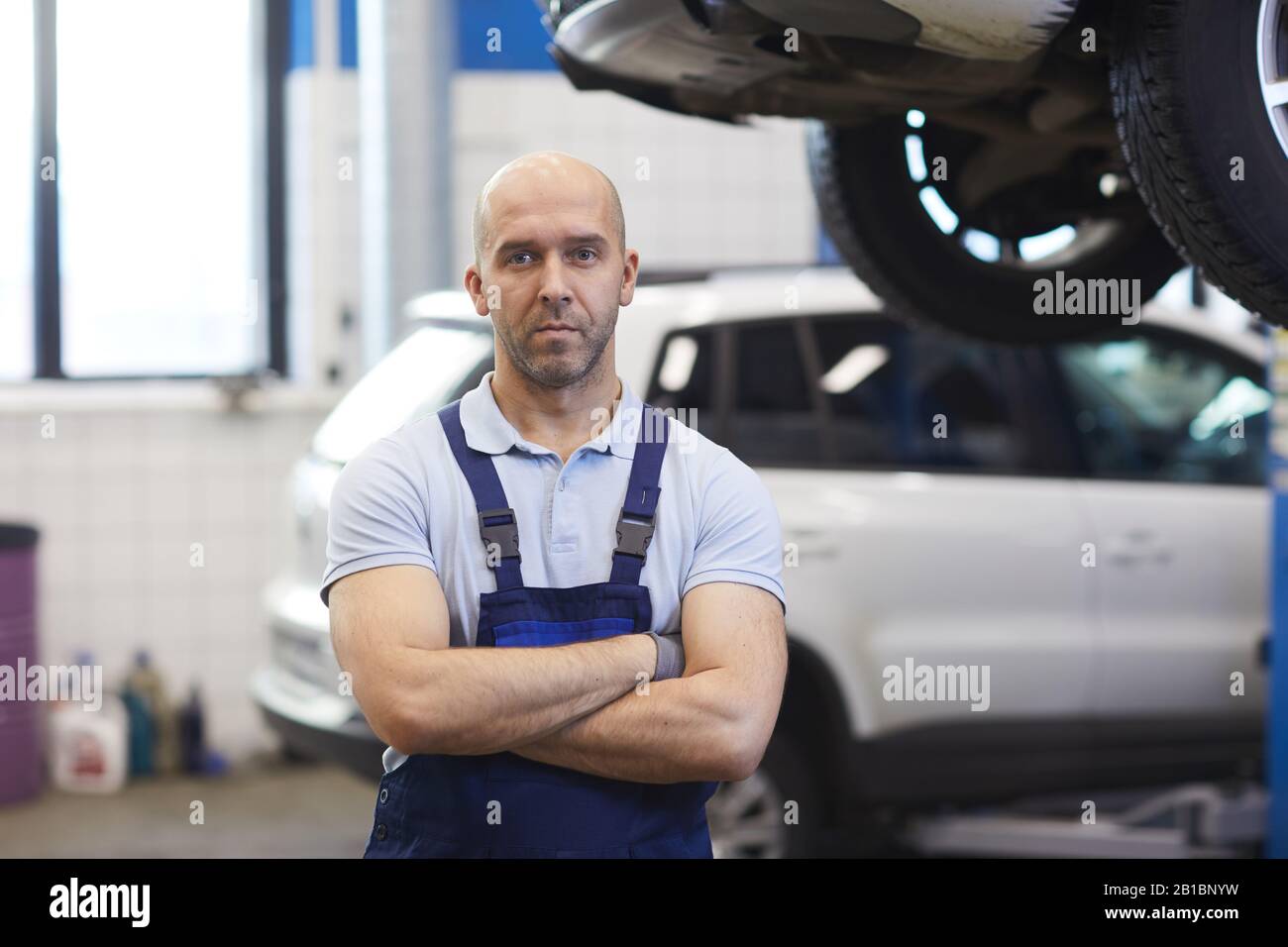 Waist up portrait of muscular car mechanic standing with arms crossed ...