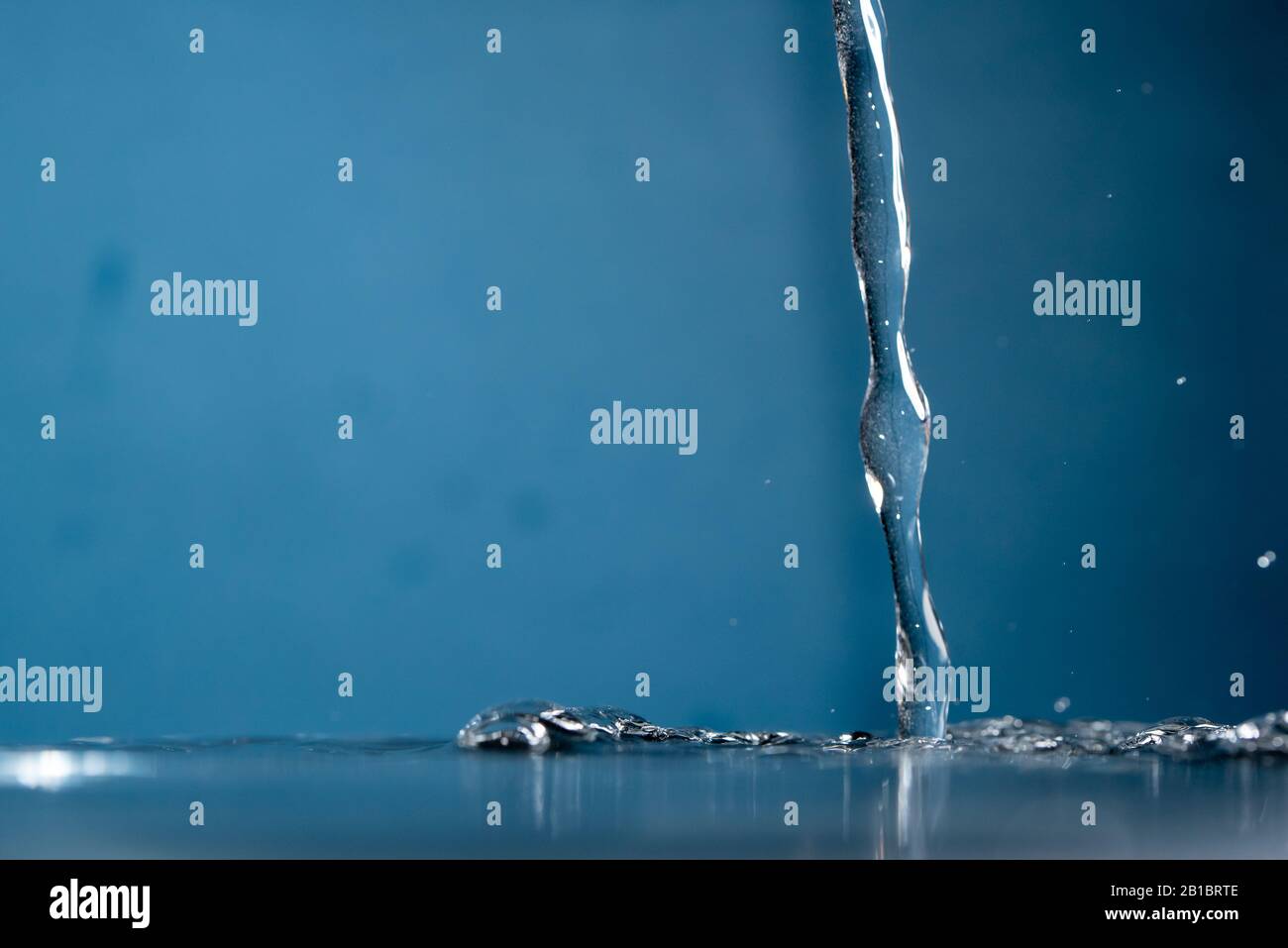 Fresh clear water running on a blue background Stock Photo - Alamy