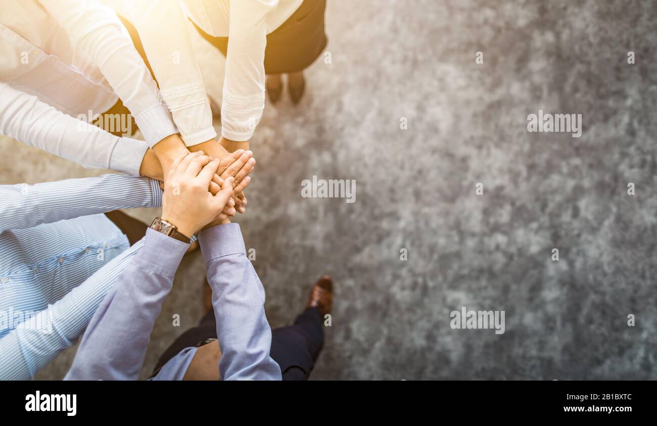 Close up top view of young business people putting their hands together ...