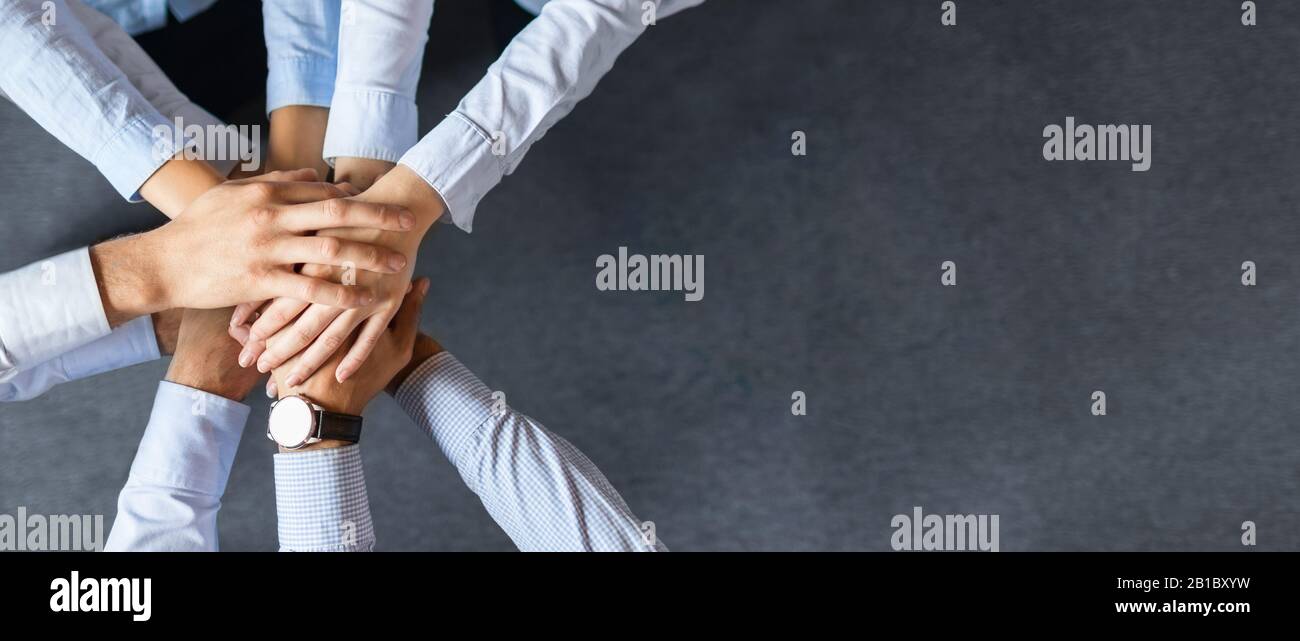 Close up top view of young business people putting their hands together ...