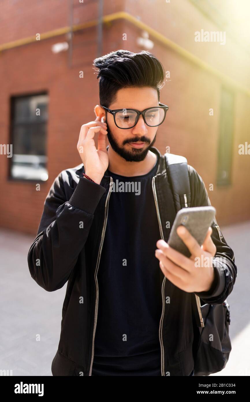 Handsome indian man with wireless headphones and speaks makes ...