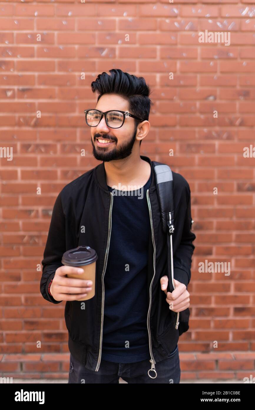 Handsome indian man with backpack and takeaway coffee on street Stock ...