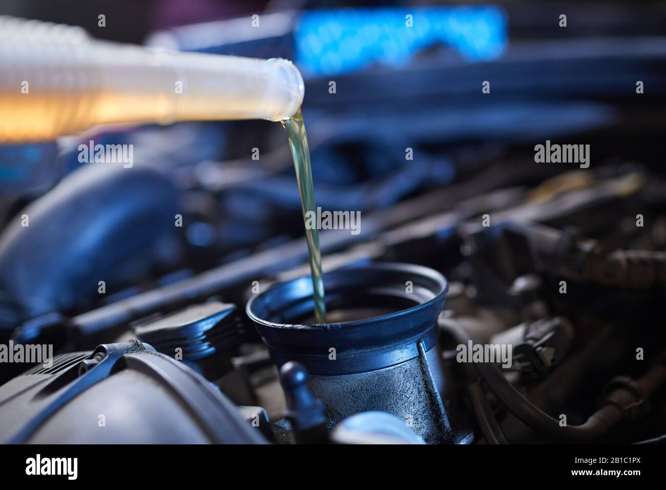 Close up background of golden stream of car oil pouring into engine ...