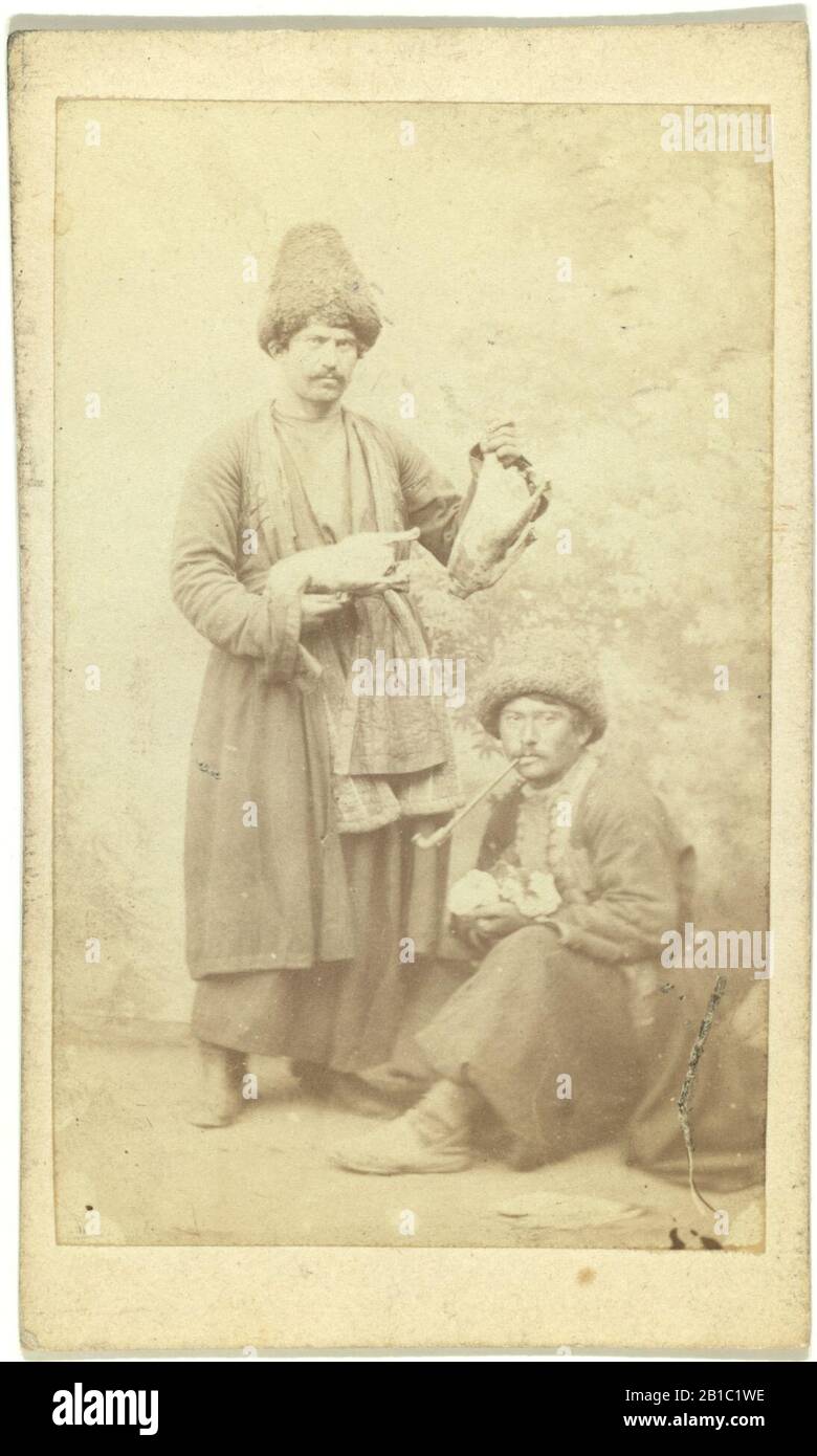 Full-length portrait of two men, one seated, one standing, facing front ...