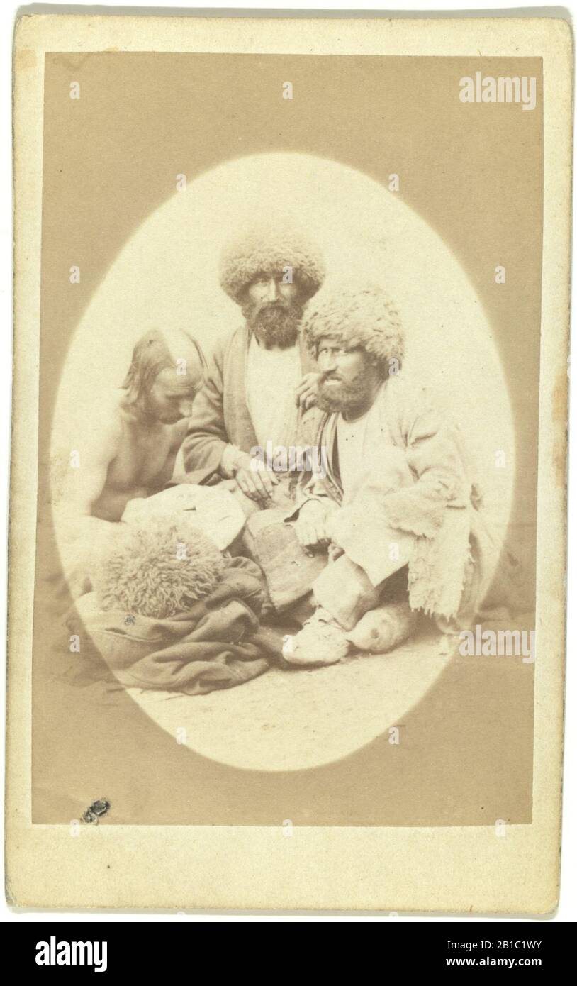 Full-length portrait of three men, seated on ground, facing front Stock ...