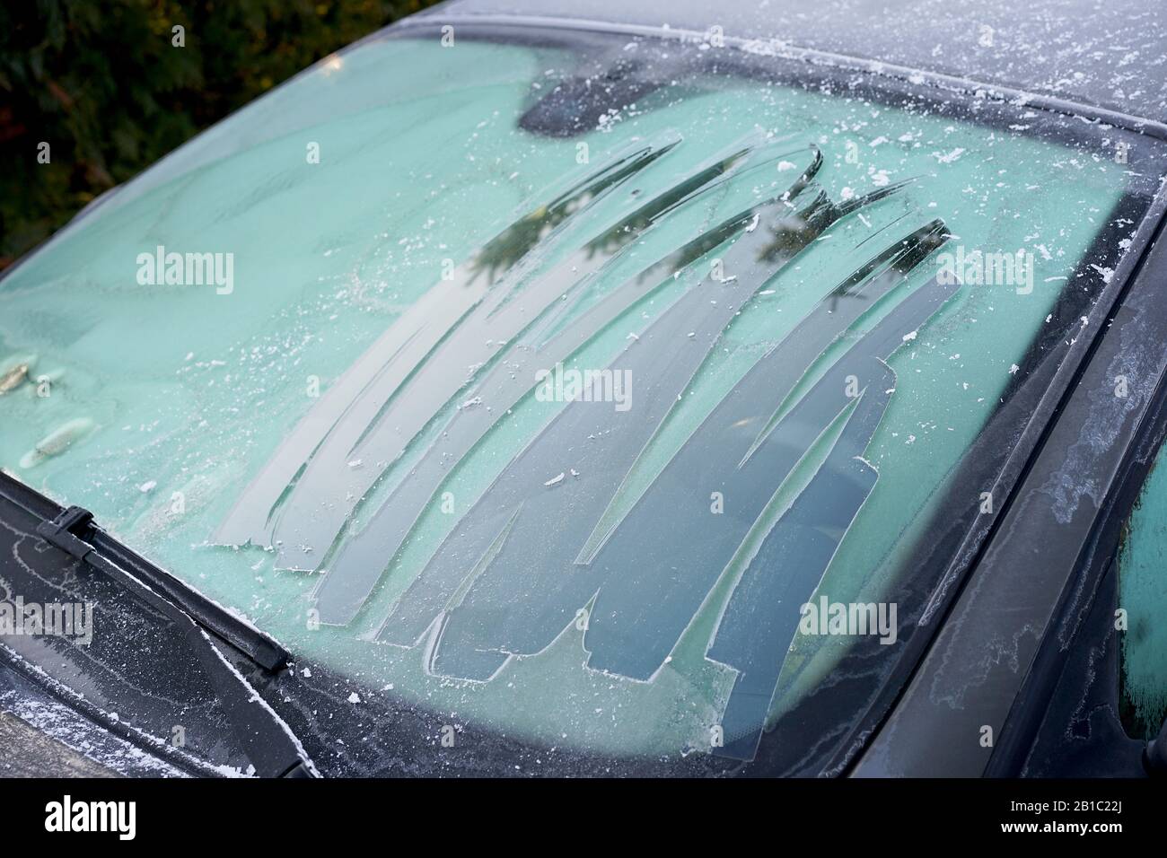 cleaning the windshield of the car from ice on a cold winter morning ...