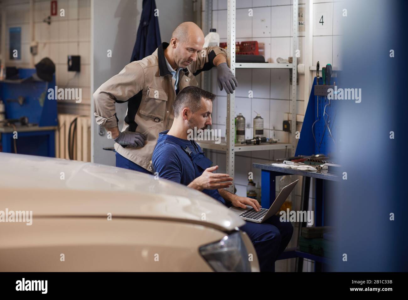 Portrait of two car mechanics using laptop while working in auto repair ...