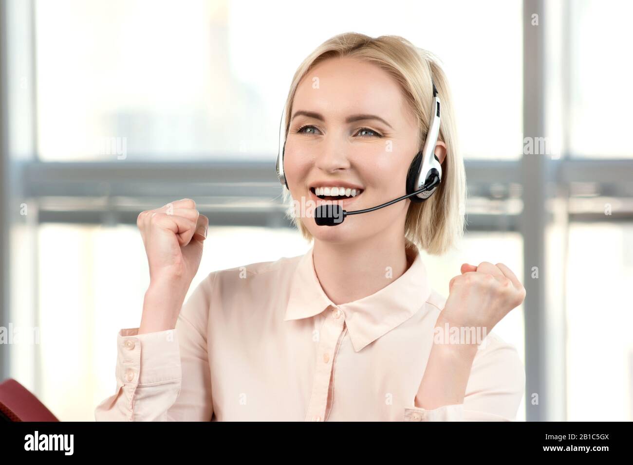 Female call center operator celebrating with fists Stock Photo - Alamy