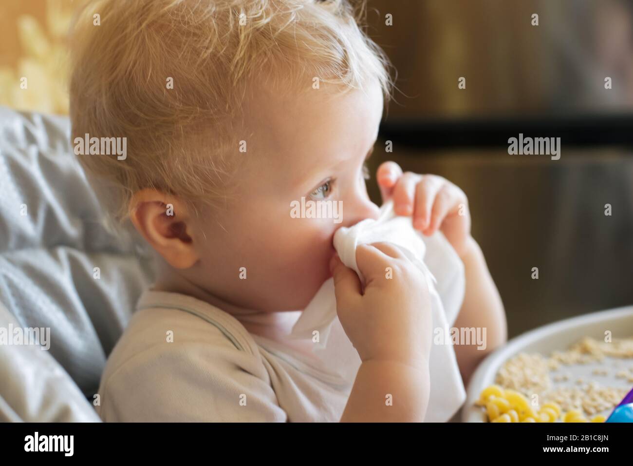 child wipes his nose with white handkerchief. Kid with cold rhinitis ...
