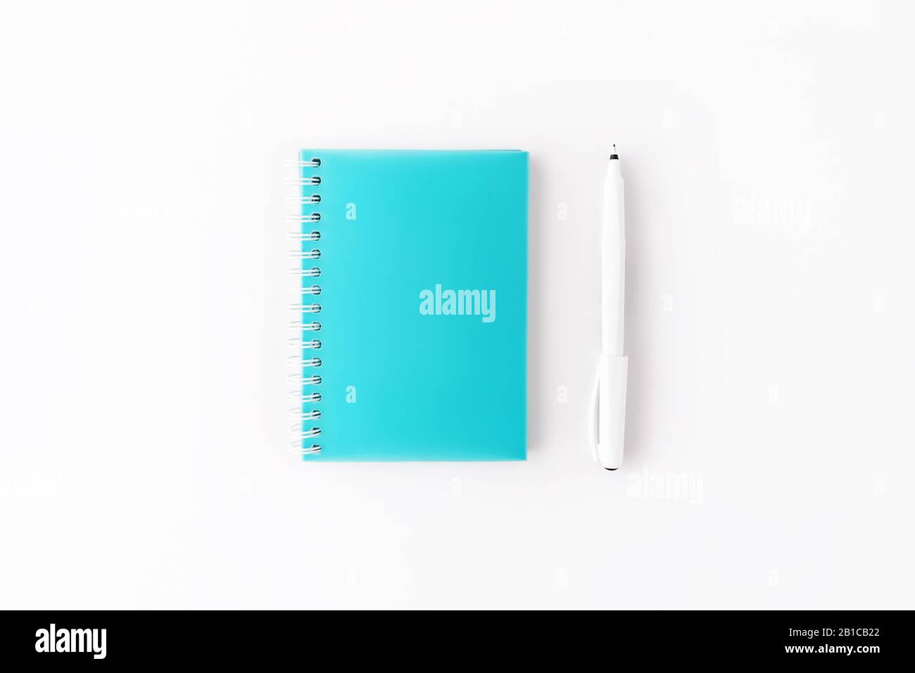 Top view of light blue cover spiral notepad with pen on white desk ...