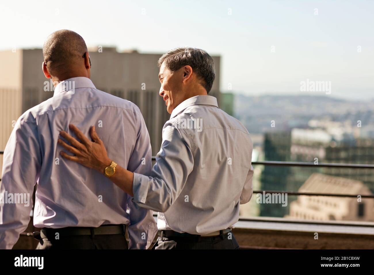 Businessmen speaking on balcony Stock Photo - Alamy