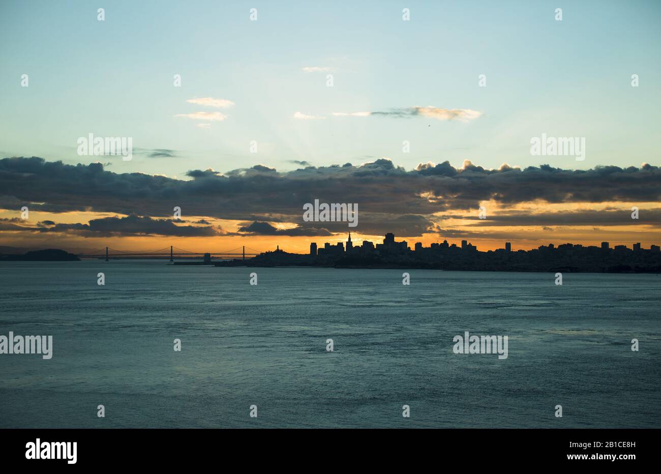 Sun setting behind the skyline of a large city Stock Photo - Alamy