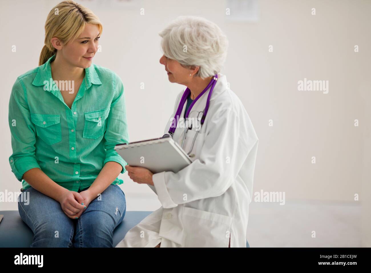 Happy young woman and a female doctor having a discussion while sitting ...