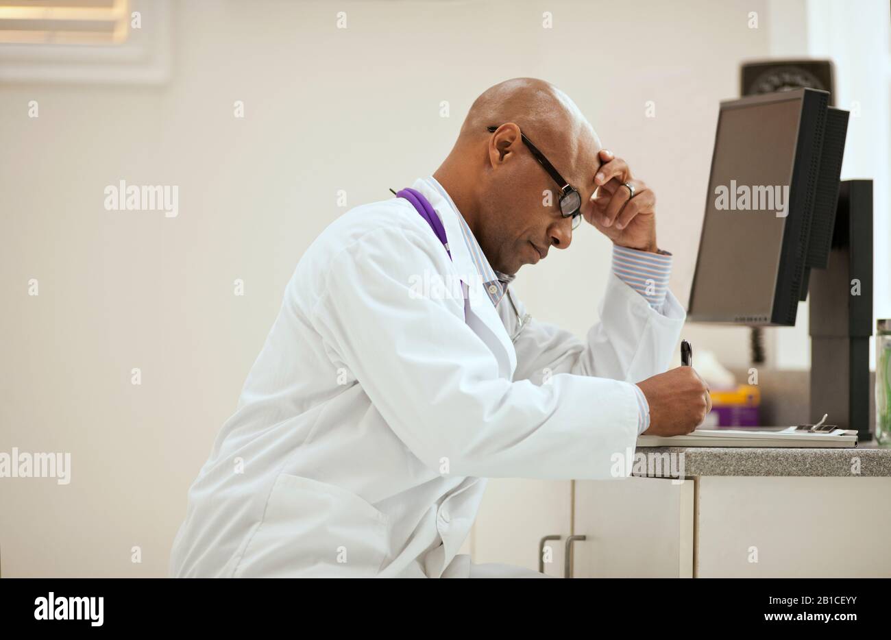 Focused male doctor taking notes while sitting inside his office Stock ...
