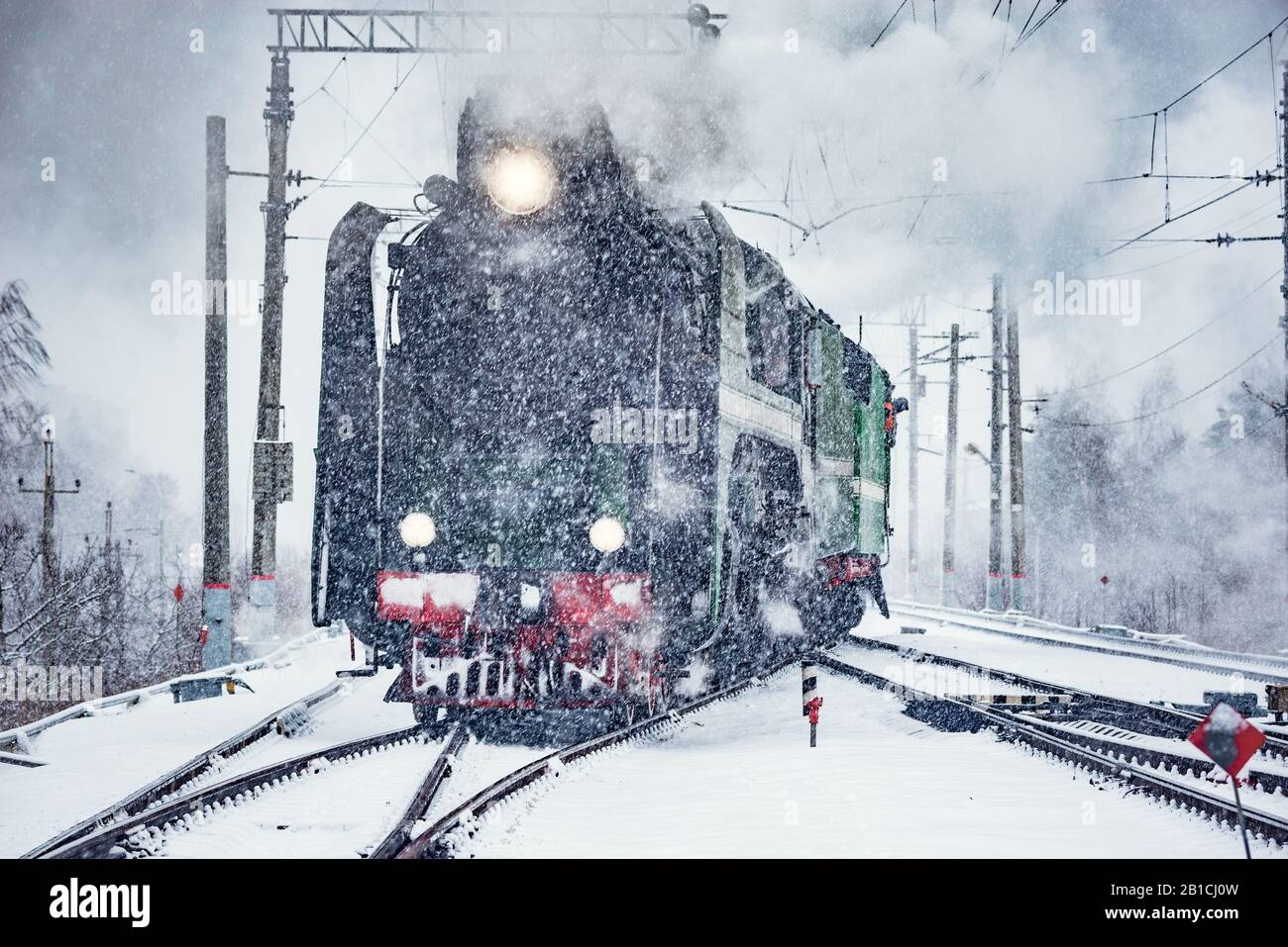 Retro steam train departs from the railway station at winter snowy time ...