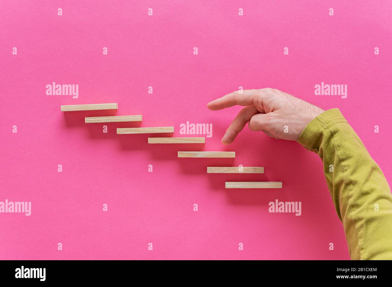 Male hand walking its fingers up the steps made of wooden pegs. Over ...
