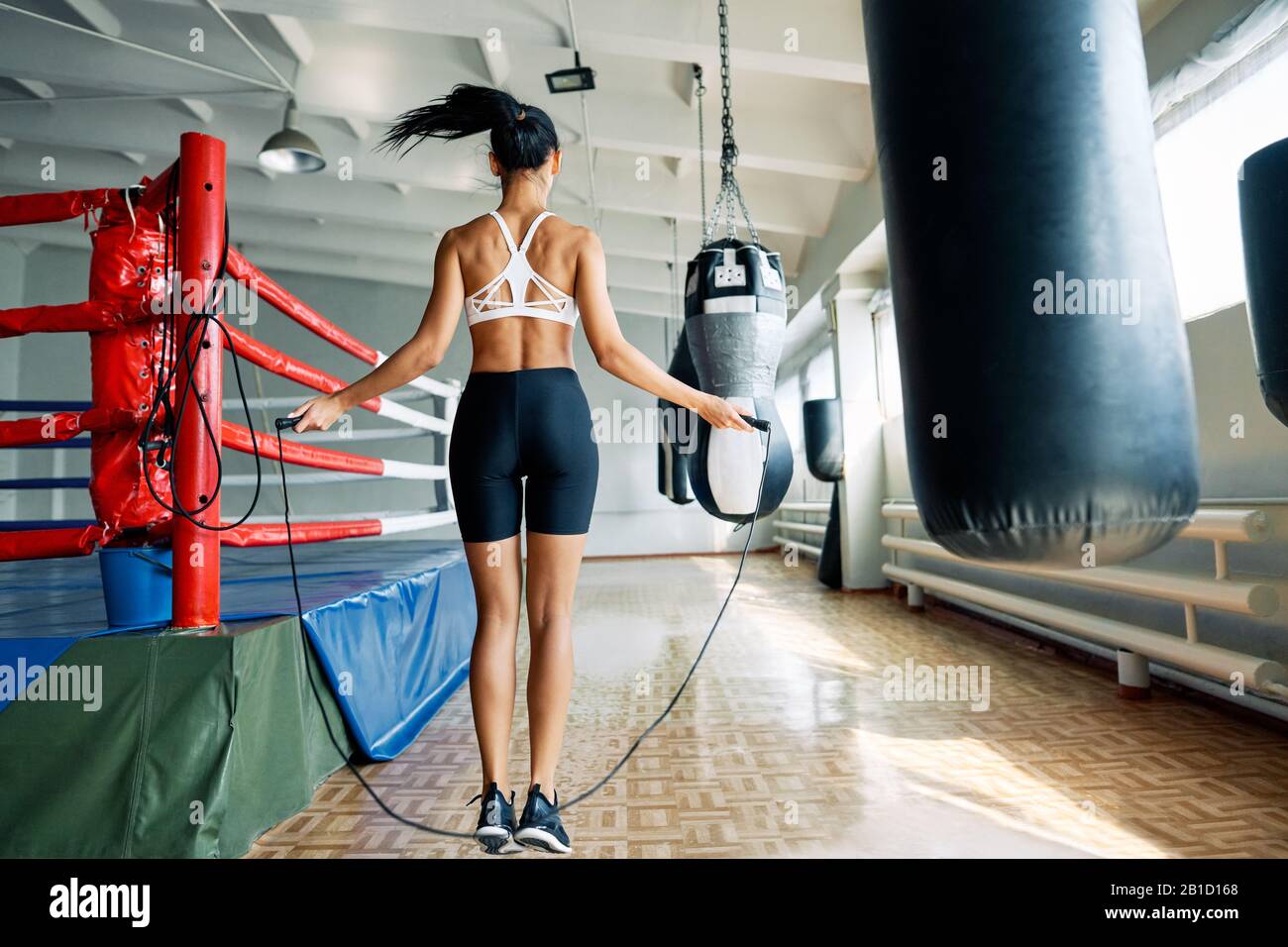 Back view of fitness woman skipping rope in gym. Cardio and fitness ...