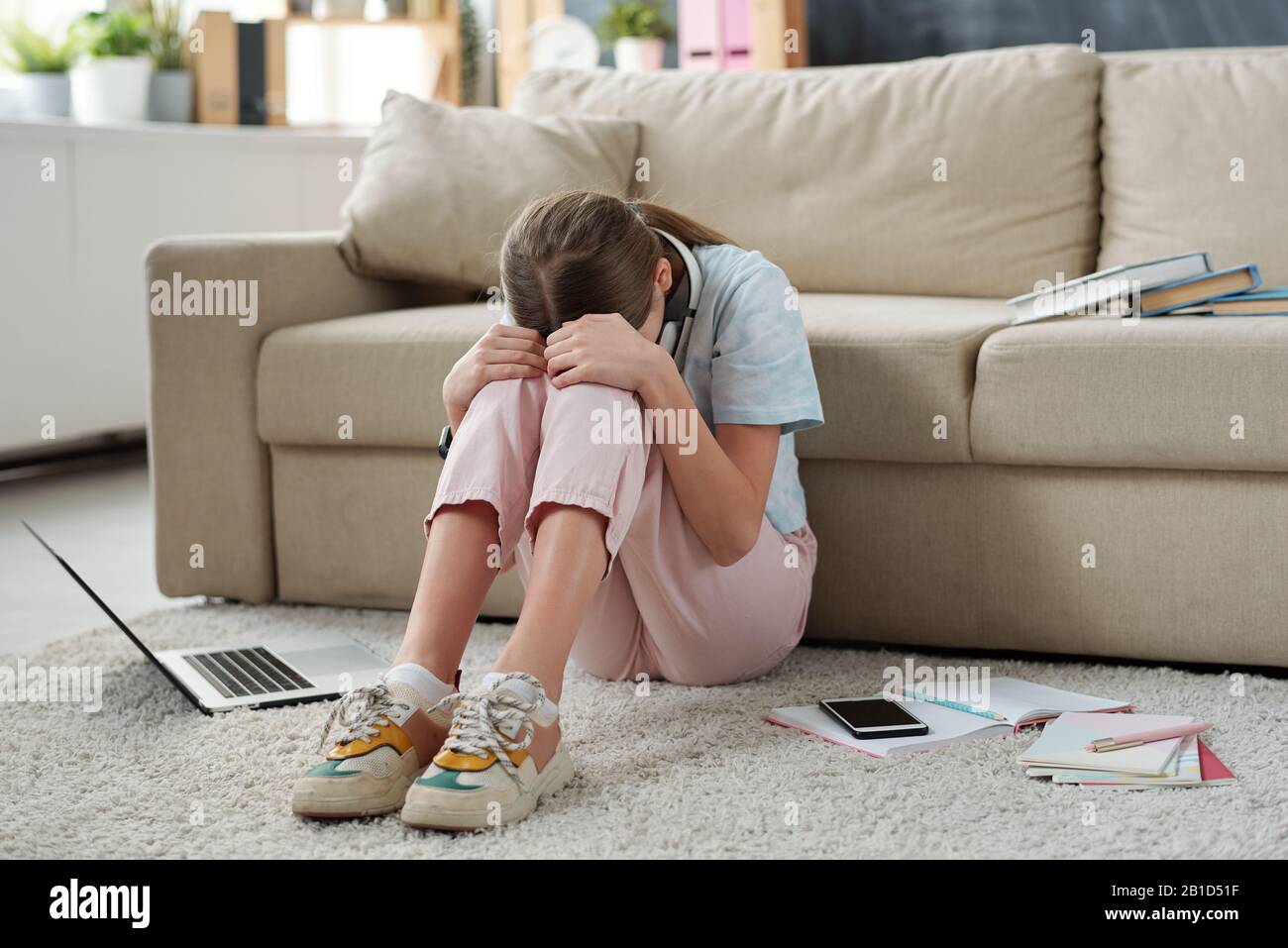 Sad exhausted teenager sitting on carpet with workbooks and crying in ...