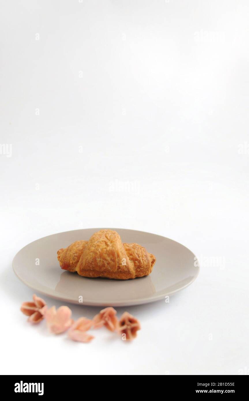 Little croissant on the plate with decorated flowers on white ...