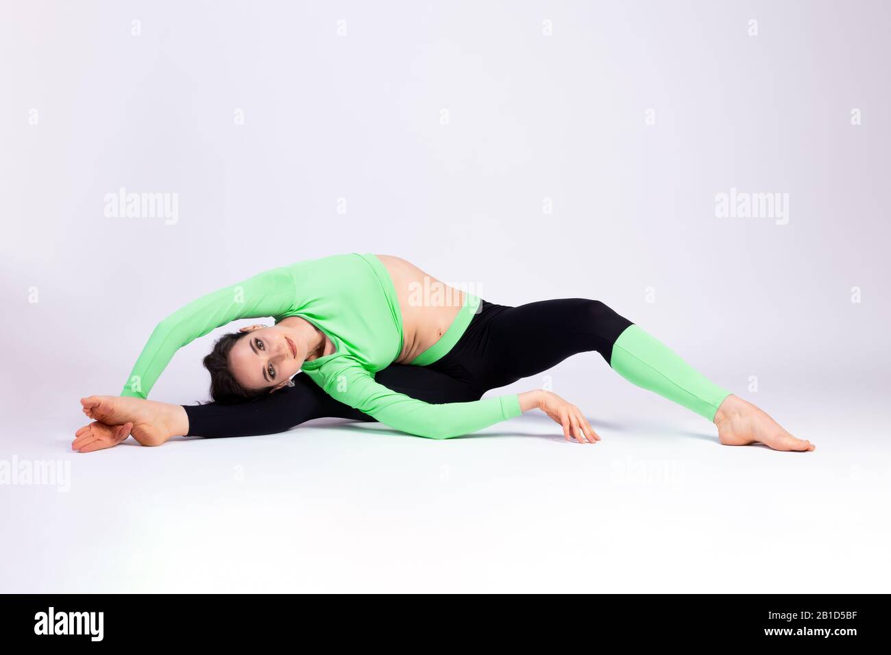 Slim young woman doing yoga practice, doing the splits on a white ...