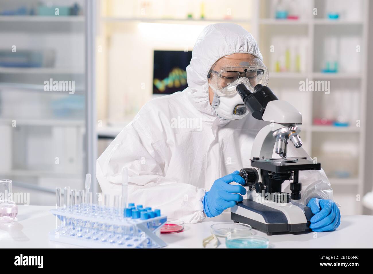 Asian medical scientist in respirator and safety goggles using ...