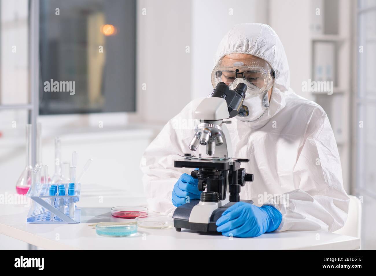 Concentrated Asian virology research scientist in protective suit, mask ...