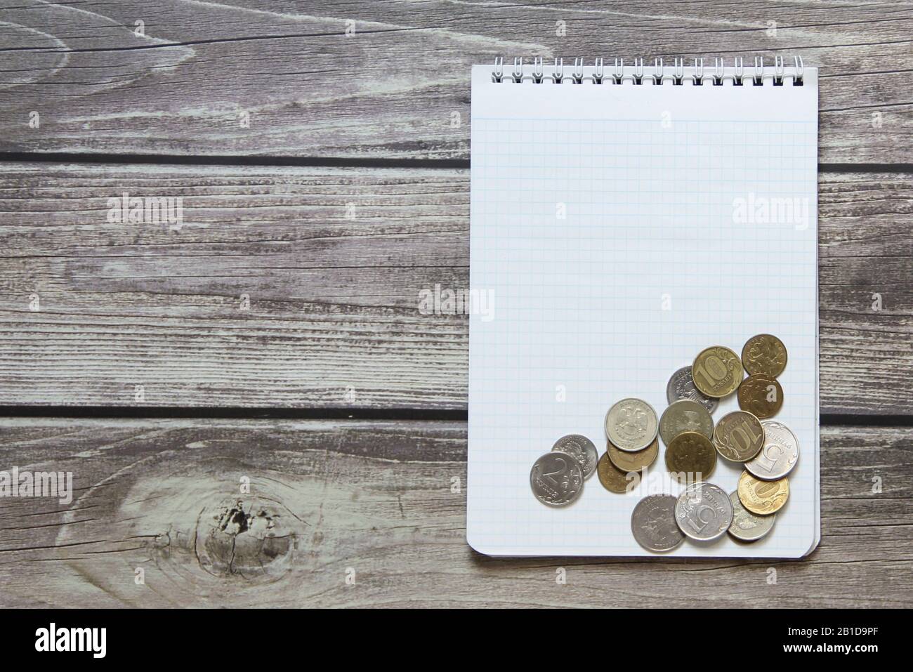 Notepad with a blank white sheet in a checker paper with russian coins ...