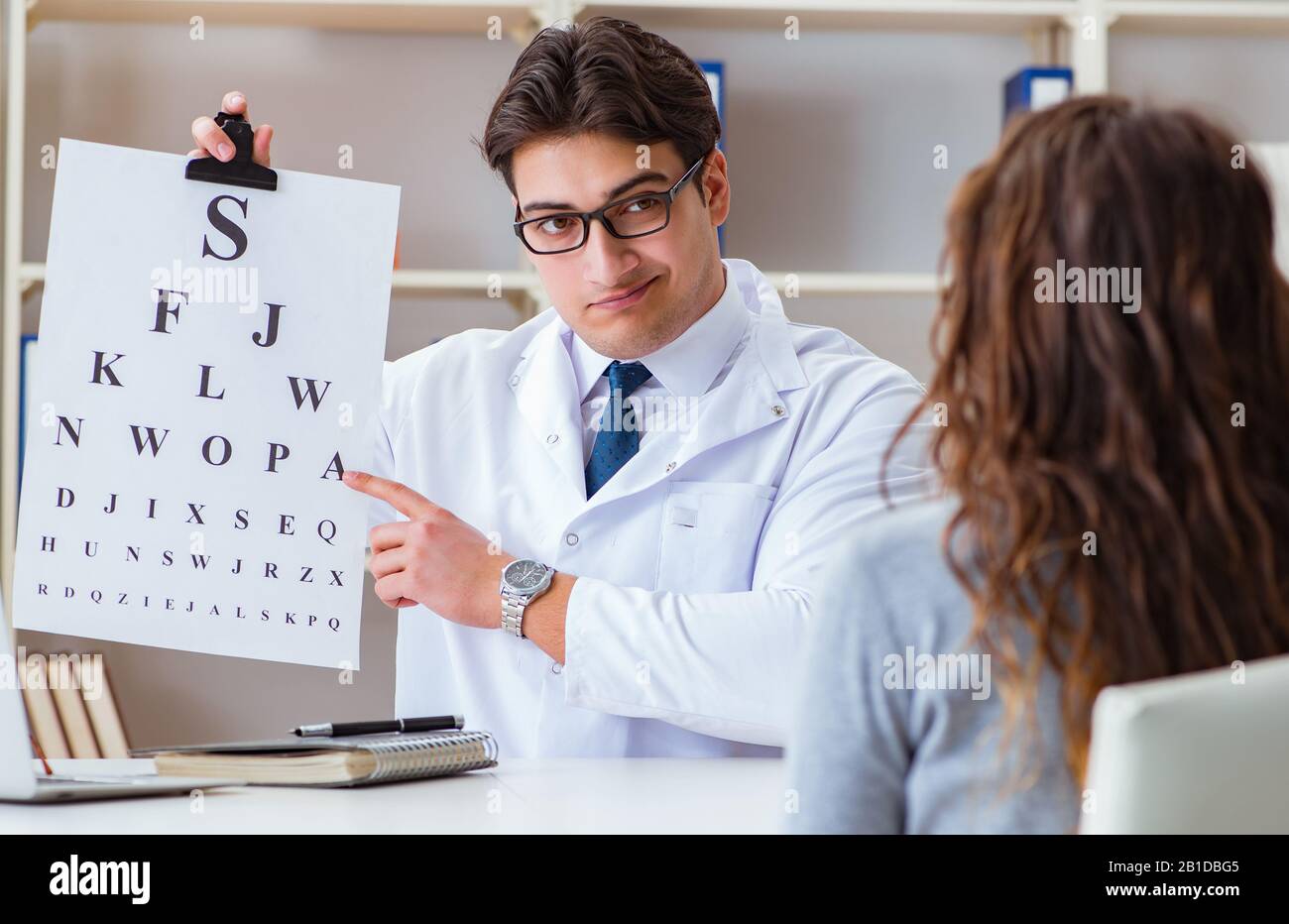 The doctor optician with letter chart conducting an eye test check ...