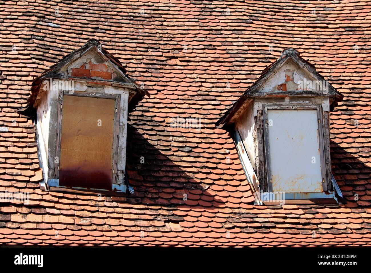 Front view of two old style roof windows closed with wooden boards ...