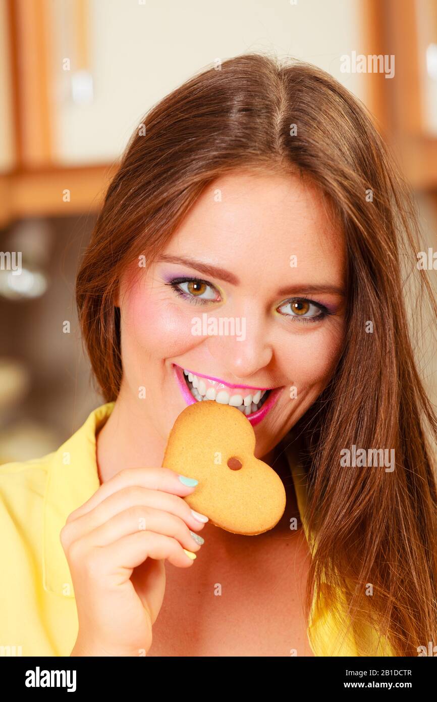 Pretty girl biting heart shape gingerbread cookie. Gorgeous woman ...