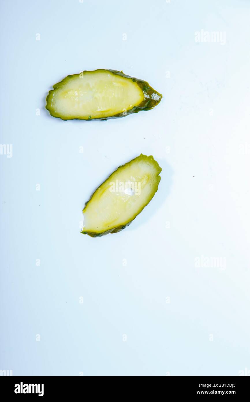 two thin oval slices of pickle on a white background Stock Photo - Alamy