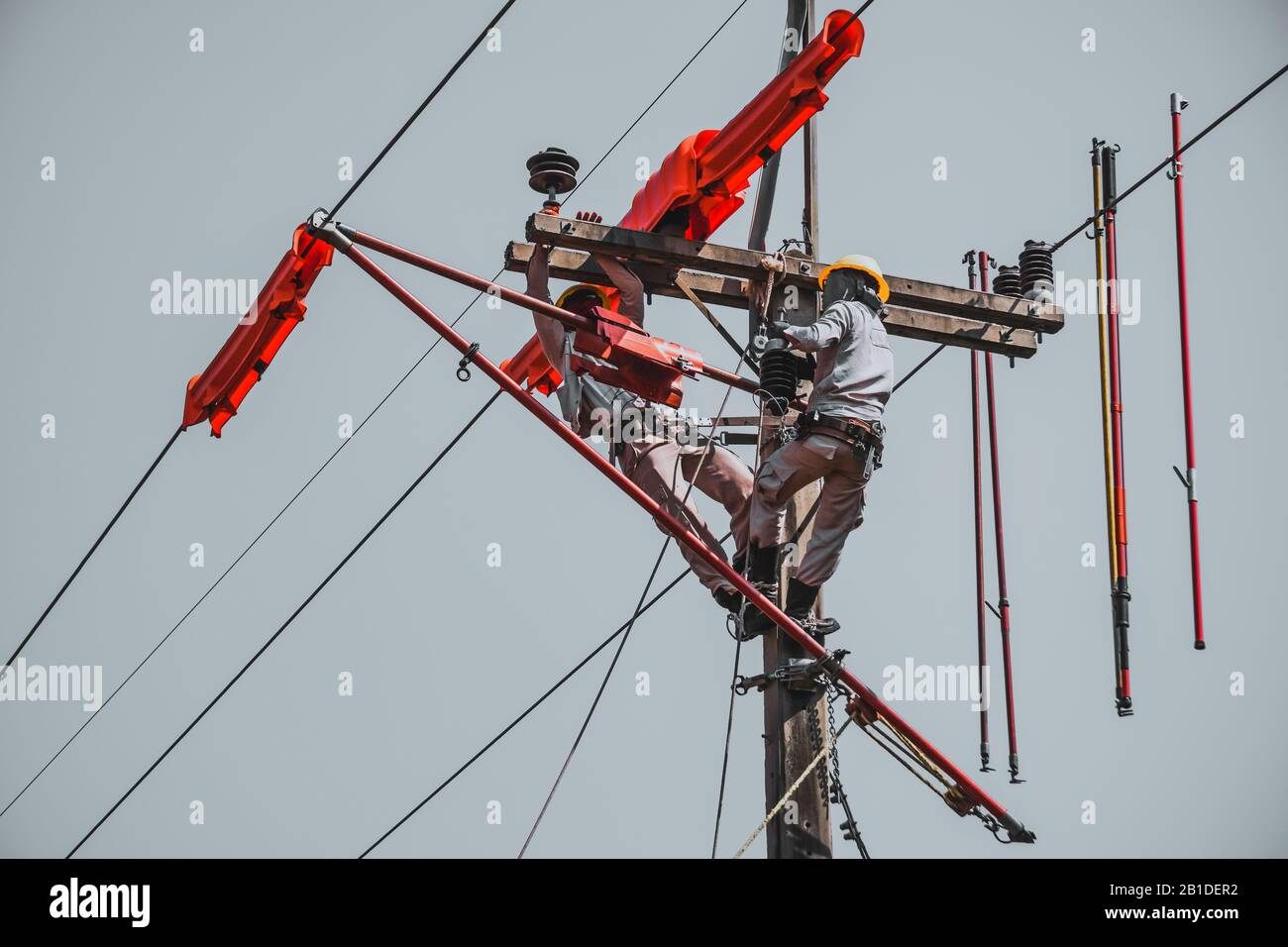 Two linemans use devices that are insulated for maintenance high ...