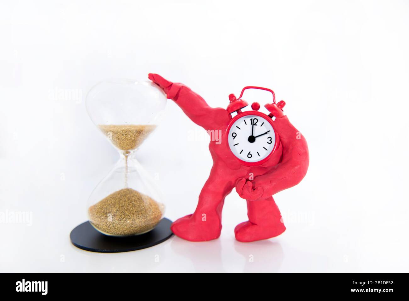 Funny red Clock with hourglass on white table. Daylight Saving Time ...