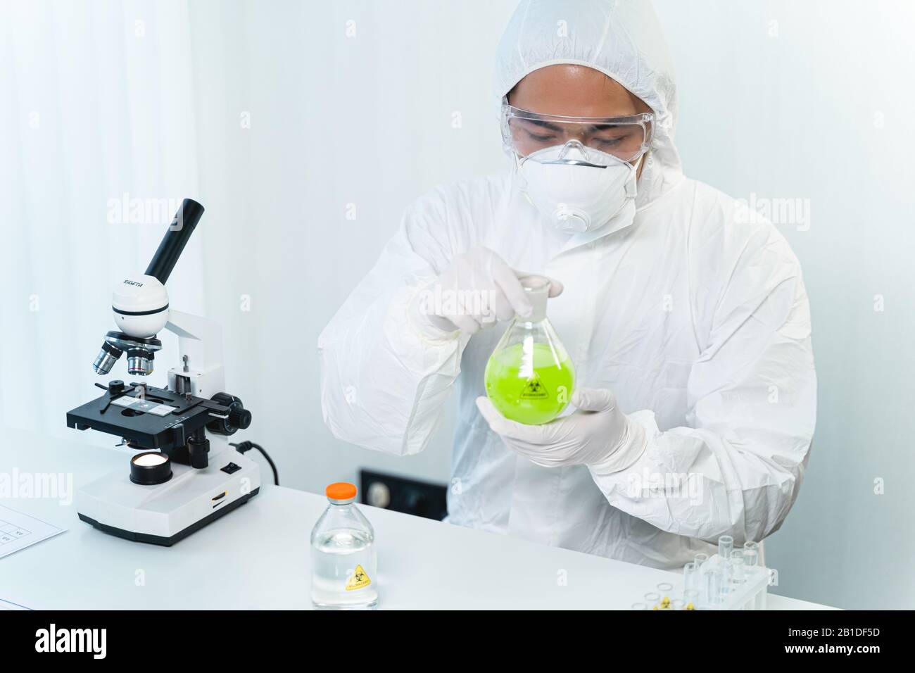 Concentrated medical worker staring at chemical reagent Stock Photo - Alamy