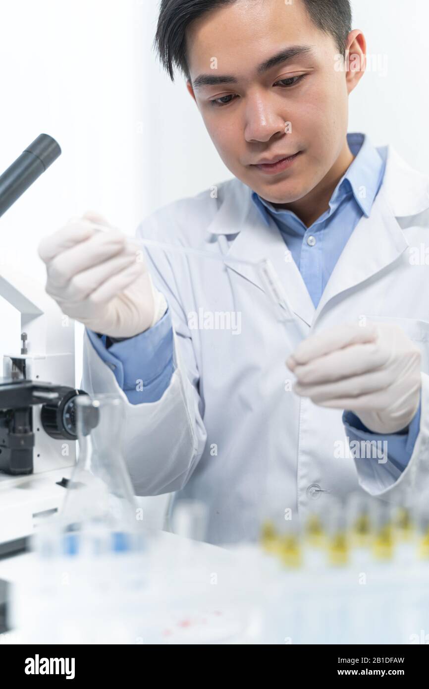 Concentrated brunette male person looking at test tube Stock Photo - Alamy