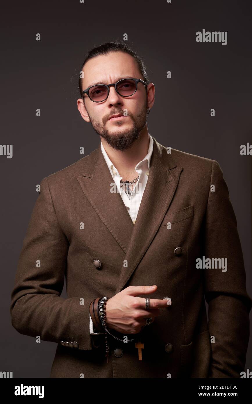 Serious man with beard in jacket looks at camera on empty brown ...