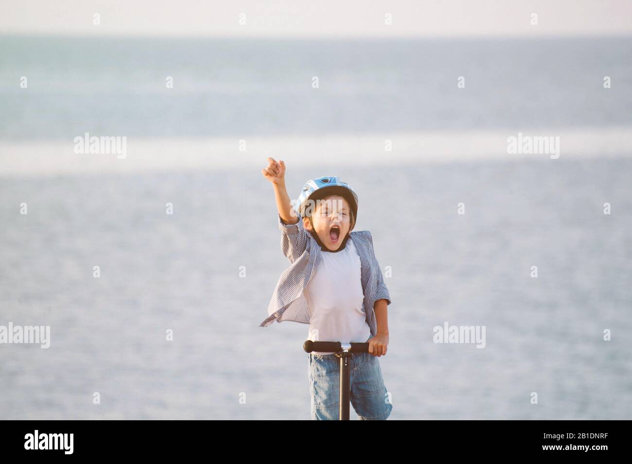 happy succeed little boy in sport helmet standing on sea background ...