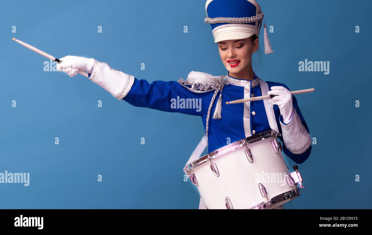 Charming cheerful drummer in a blue uniform, sings and plays the drum ...