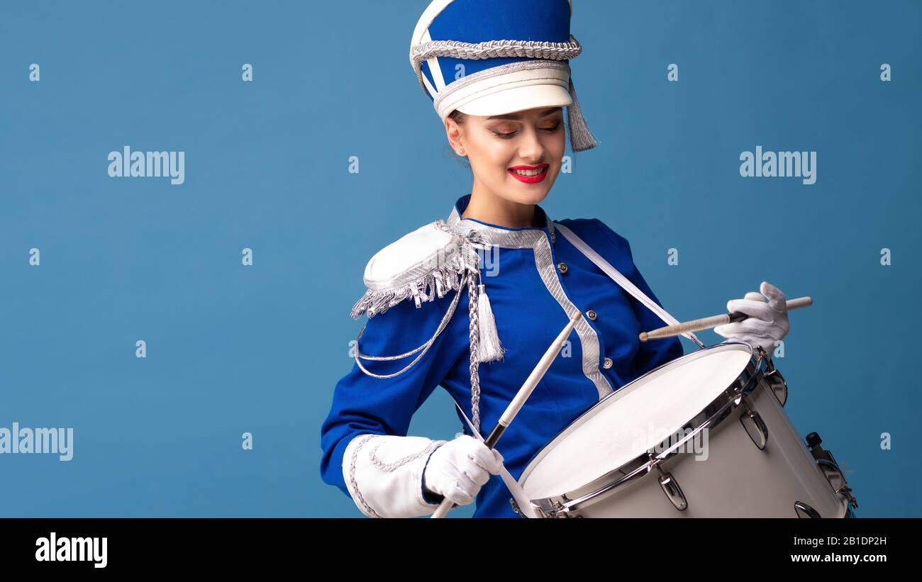 Charming cheerful drummer in a blue uniform, sings and plays the drum ...