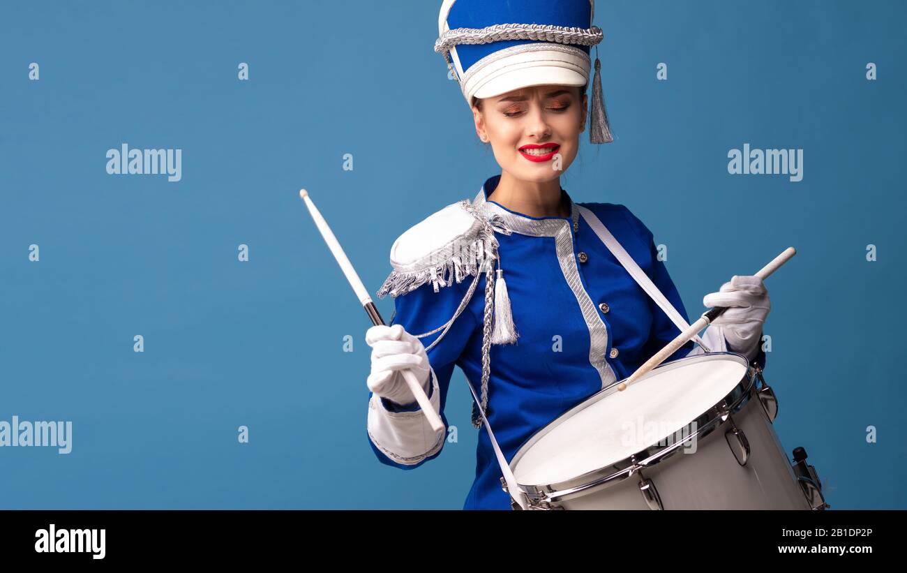 Charming cheerful drummer in a blue uniform, sings and plays the drum ...