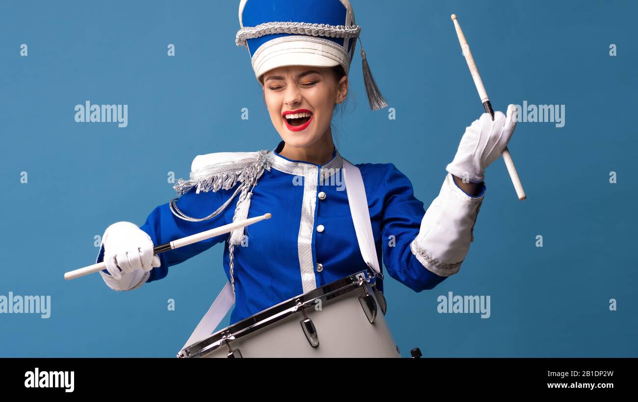Charming cheerful drummer in a blue uniform, sings and plays the drum ...