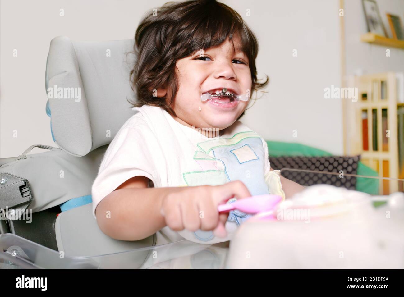 Handsome biracial disabled boy toddler sitting in wheelchair with ...