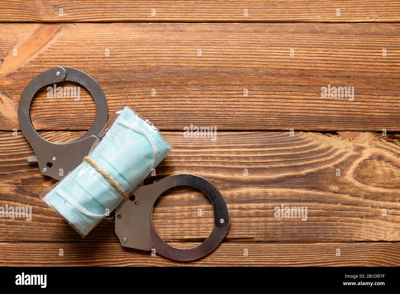 disposable medical face mask and handcuffs on a table concept of ...