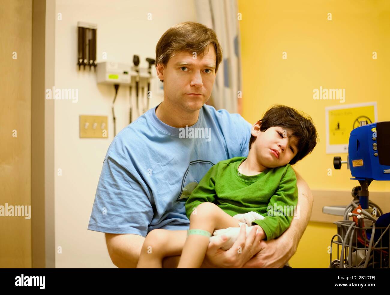 Worried Caucasian father holding biracial sick disabled son in hospital ...