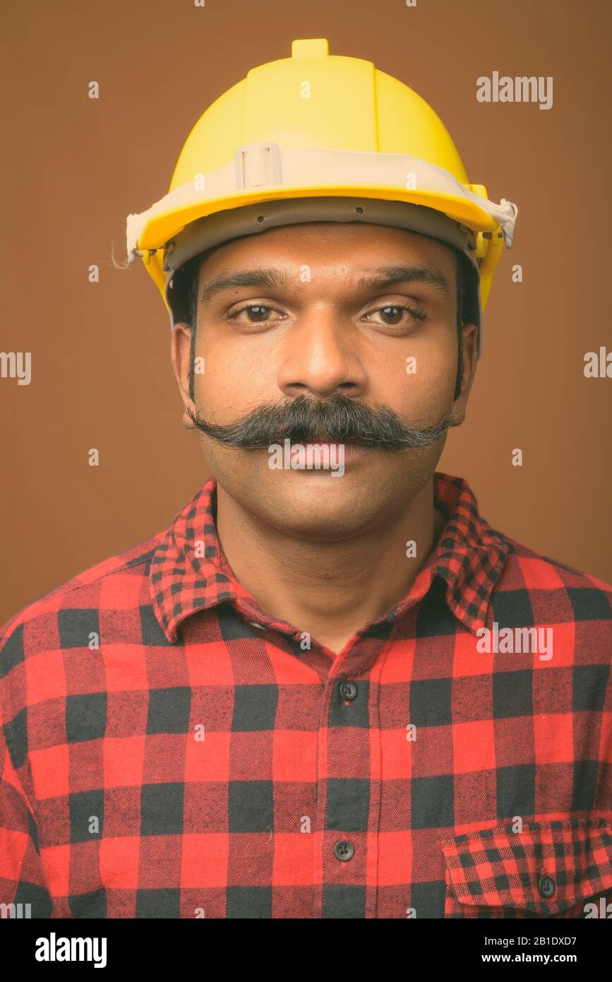 Indian man construction worker with mustache against brown background ...