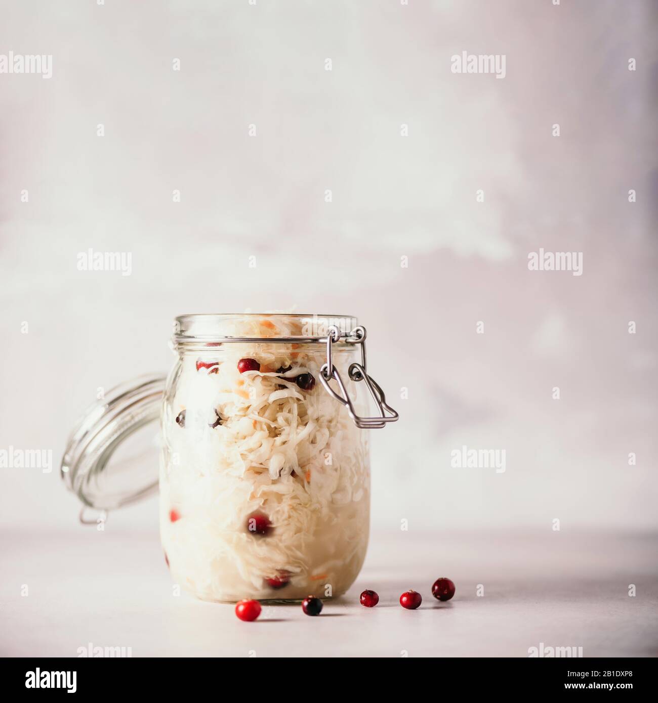 Fermented cabbage with cranberry in glass jar over grey background ...