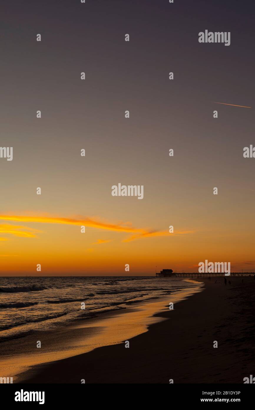 Newport Pier can be seen in the distance at sunset in Newport Beach ...