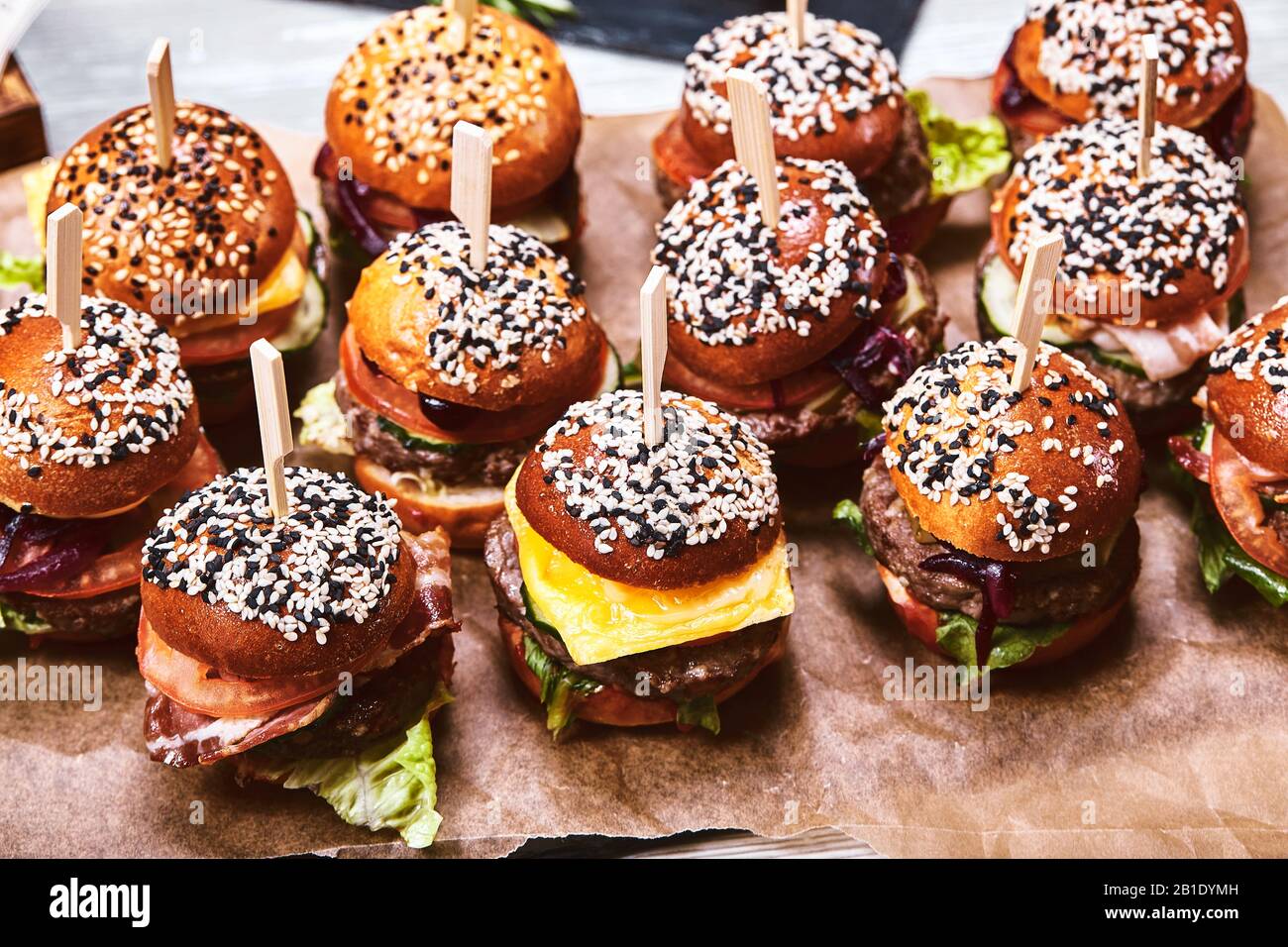 A large set of many hamburgers, cheeseburgers laid out on the table ...