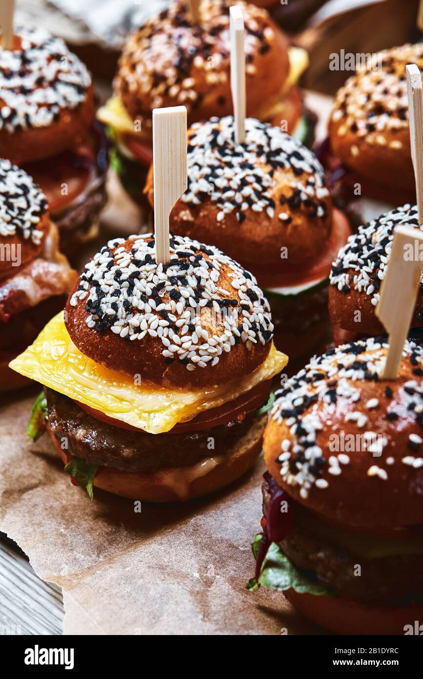 A large set of many hamburgers, cheeseburgers laid out on the table ...